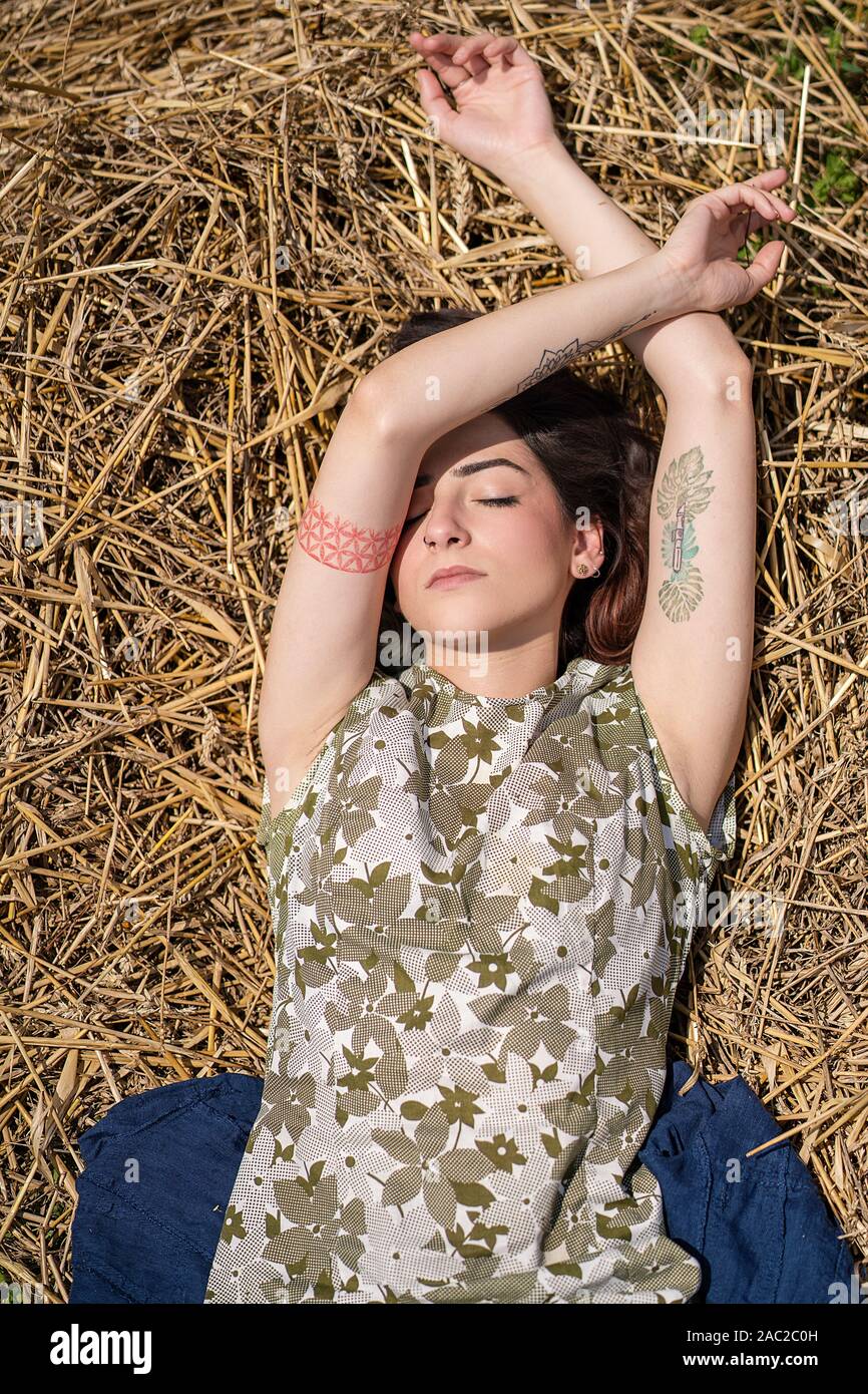 Girl lying and dreaming in a wheat field. Woman posing on hay dry grass ...
