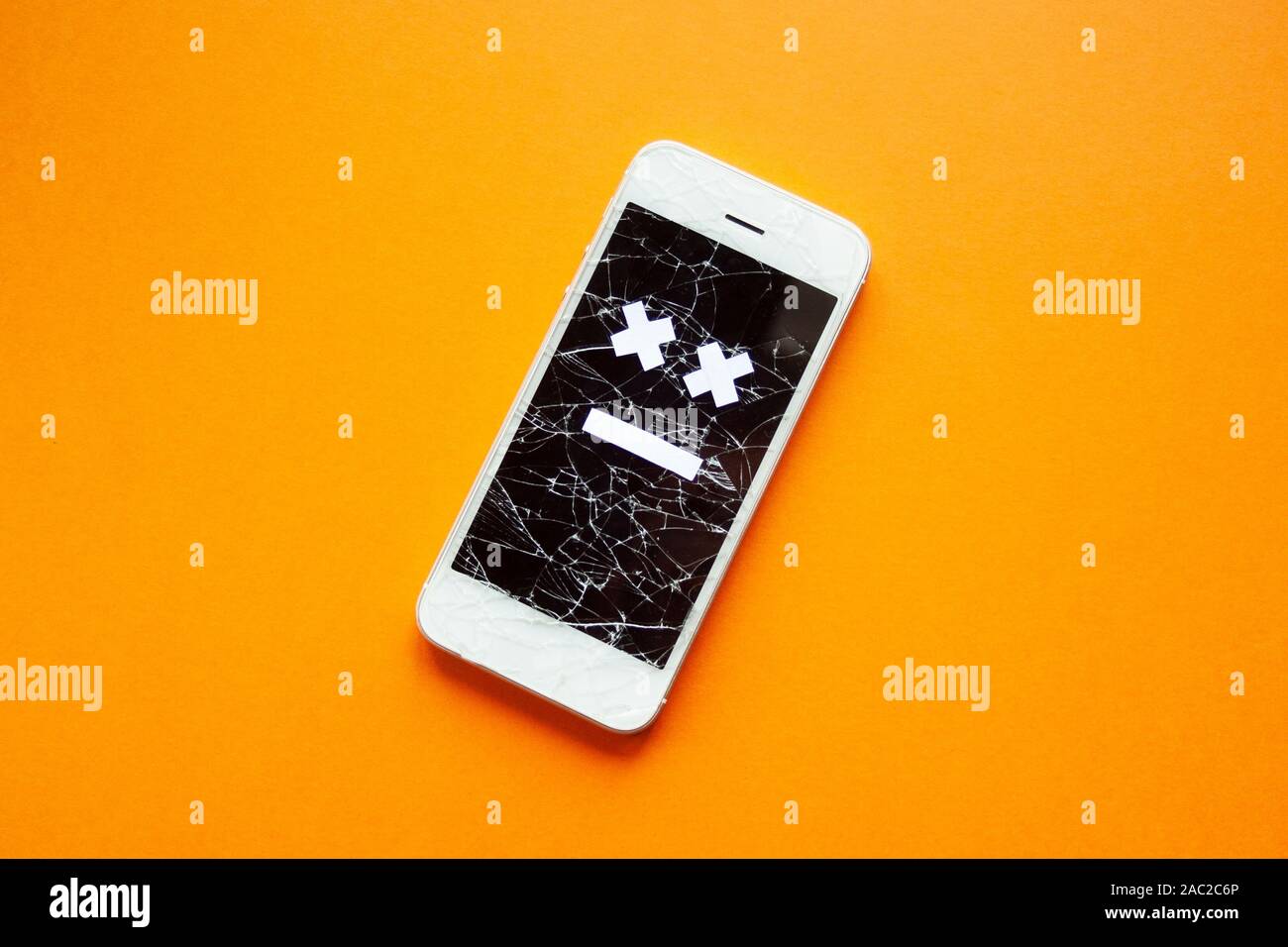 Broken smartphone with cracked destroyed screen on orange background ...