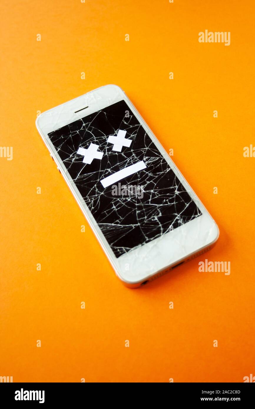 Broken smartphone with cracked destroyed screen on orange background ...