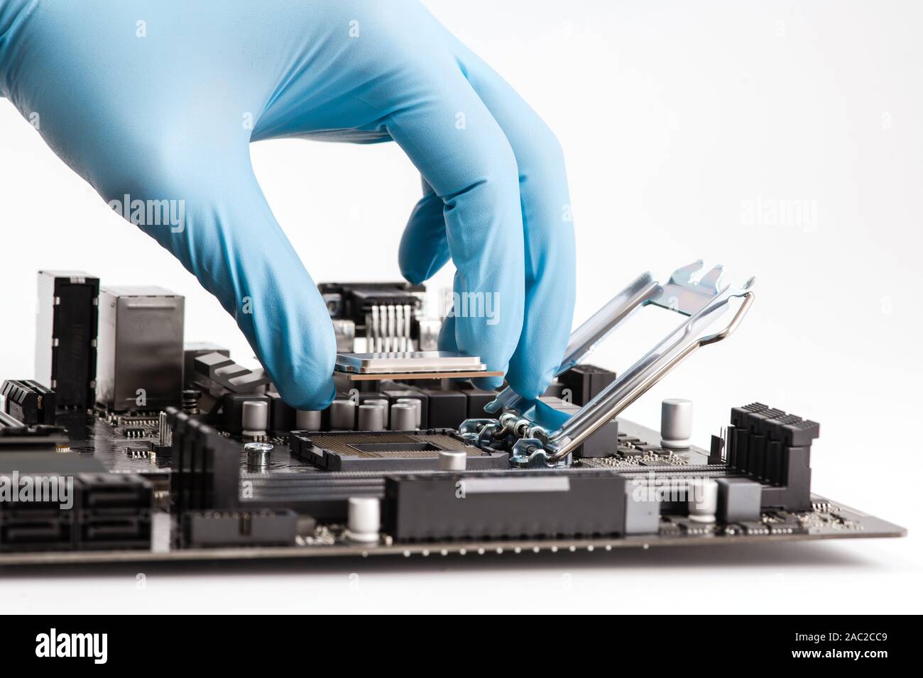 Computer technician wearing blue gloves installing CPU into motherboard ...