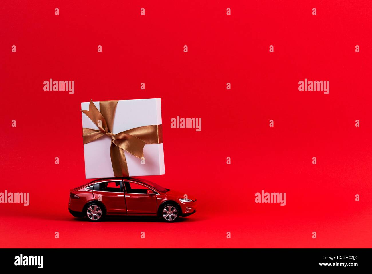 Red toy model car with present gift box on the top, red background ...