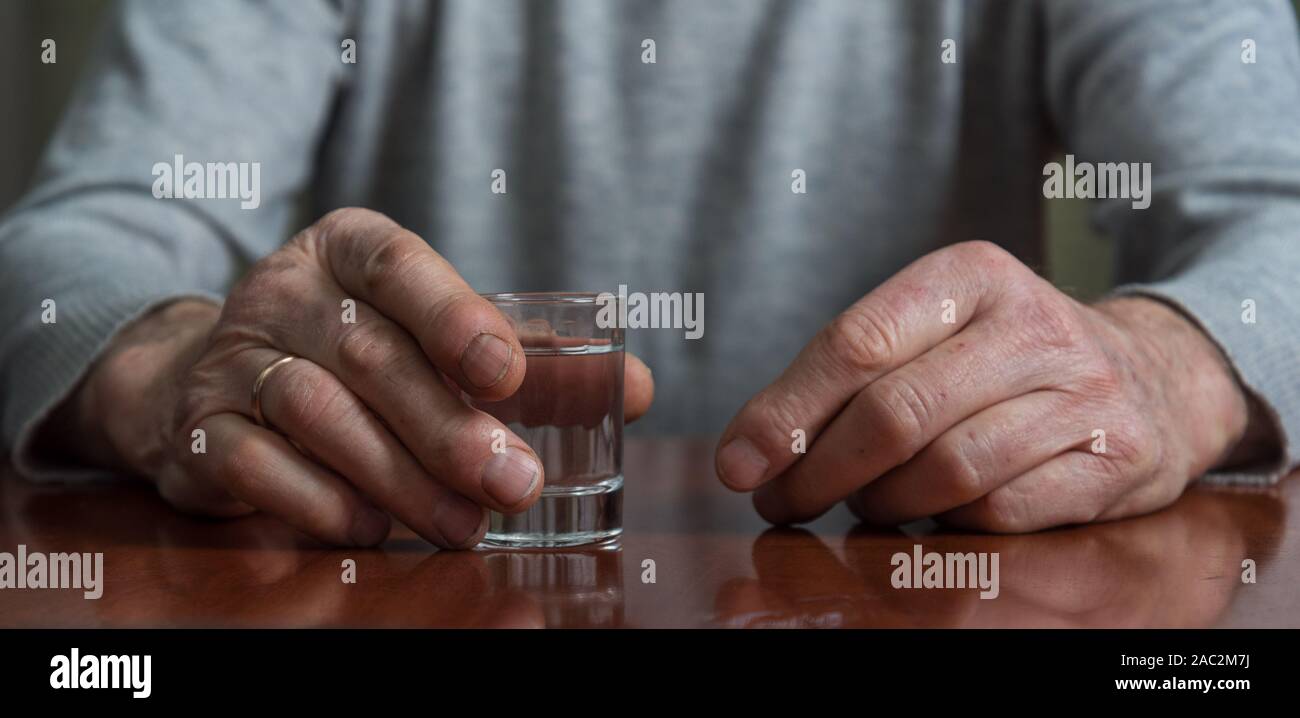 Old man at the table with small glass Stock Photo - Alamy