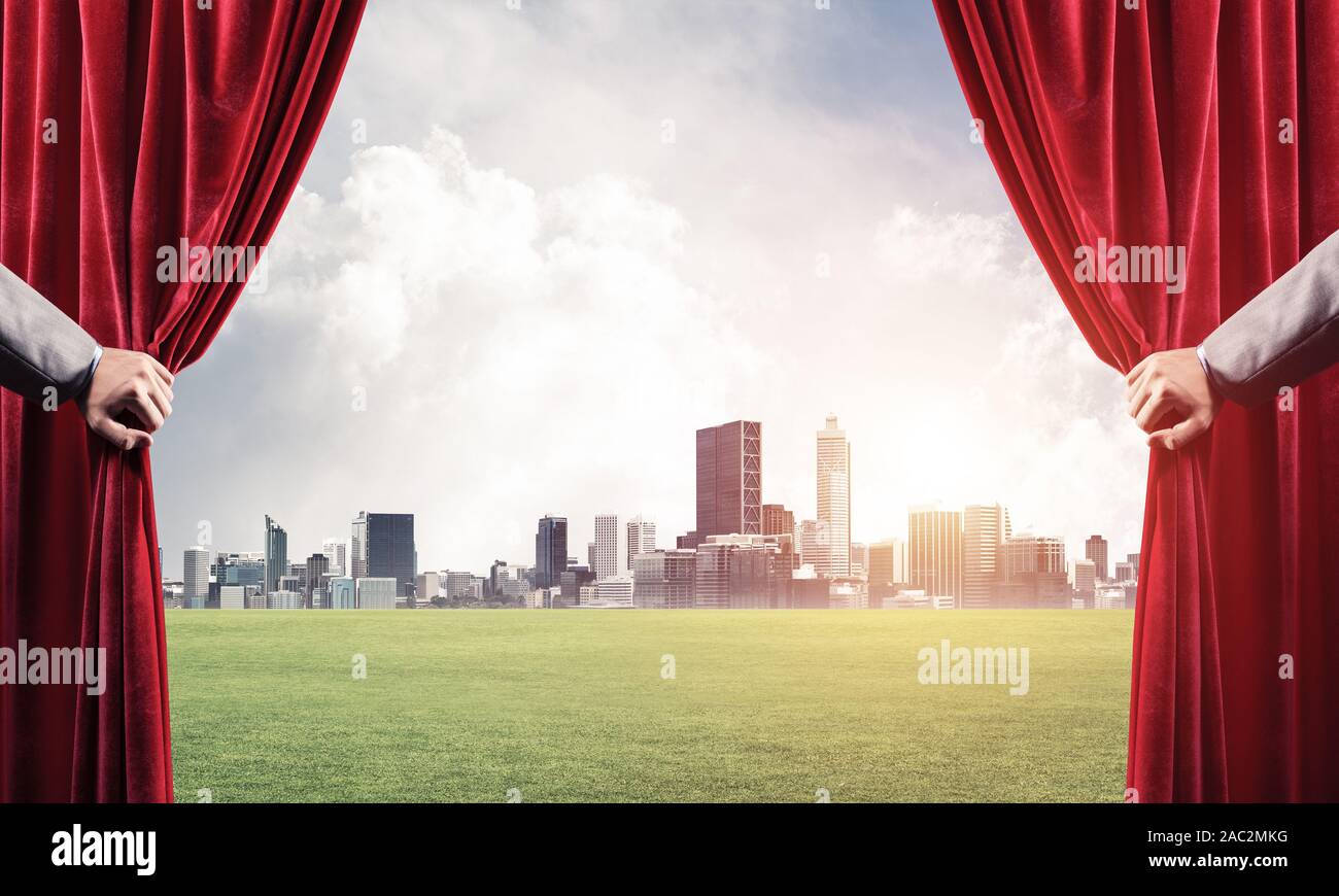 Green meadow behind red curtain and hand holding it Stock Photo - Alamy