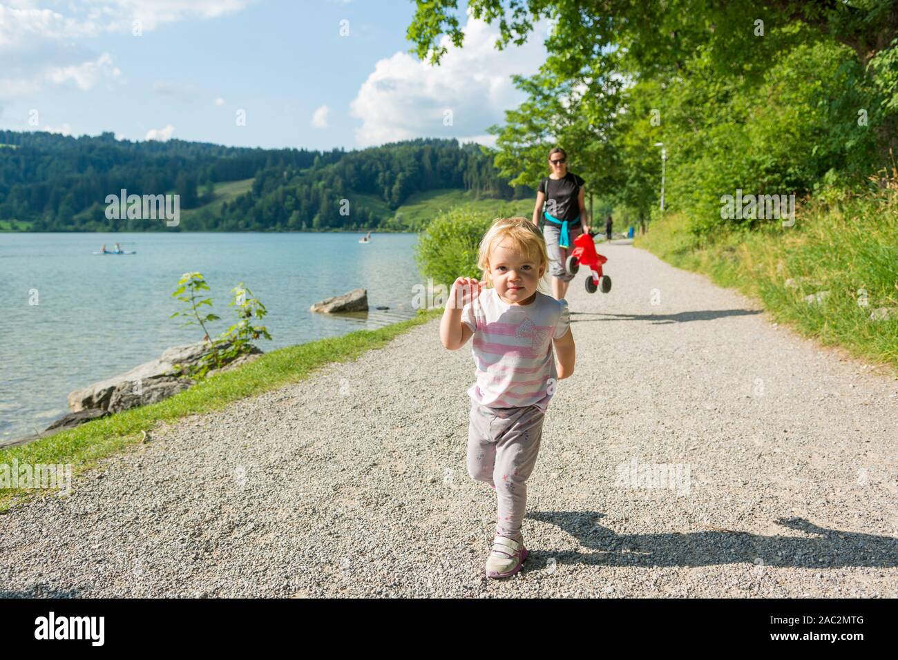 Cute blonde girl running on a path outdoor Stock Photo - Alamy