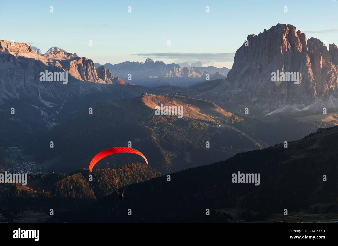 Paraglider with red parachute flies over the mountains filled with ...