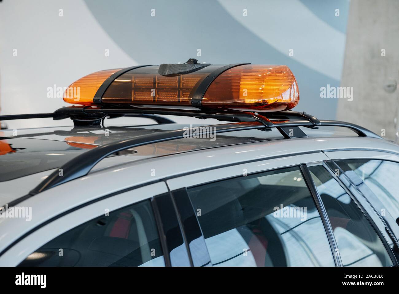 Orange blinkers at shiny white car standing indoor on a blue and white ...