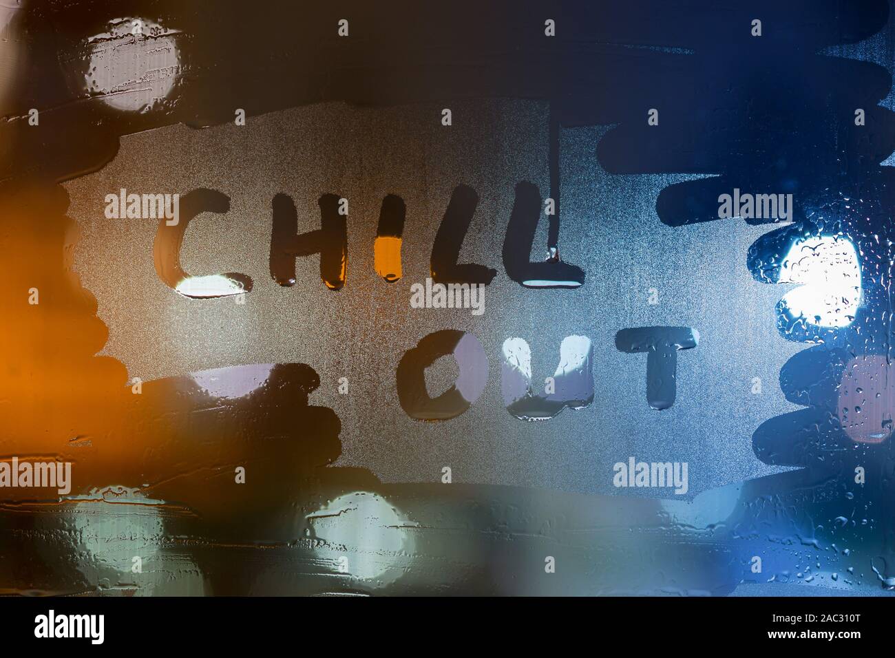 the words chill out written by finger on wet glass with blurred lights ...