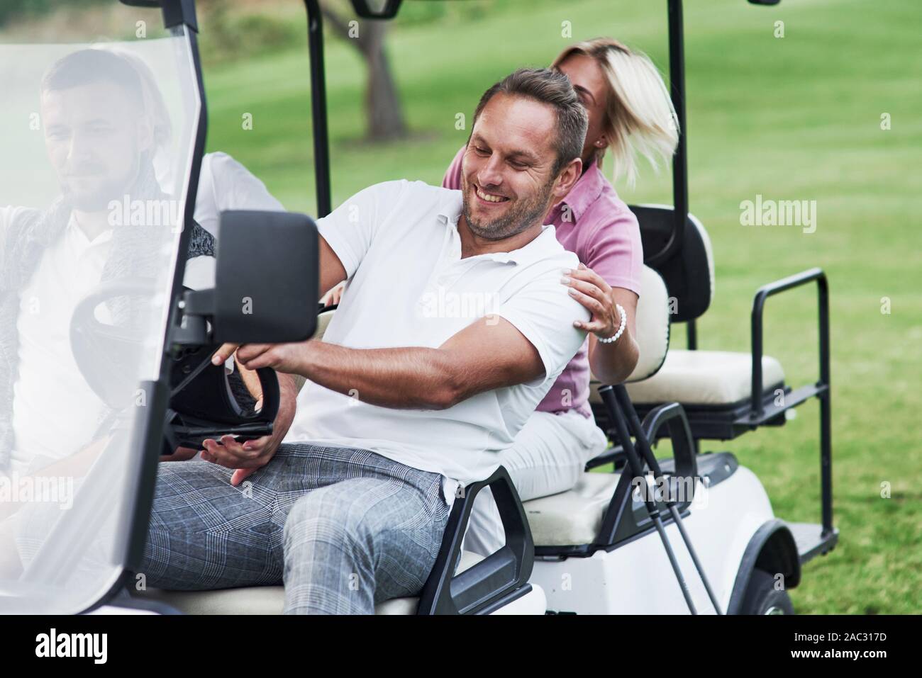 Family friends having fun riding the golf cart on the field after the ...