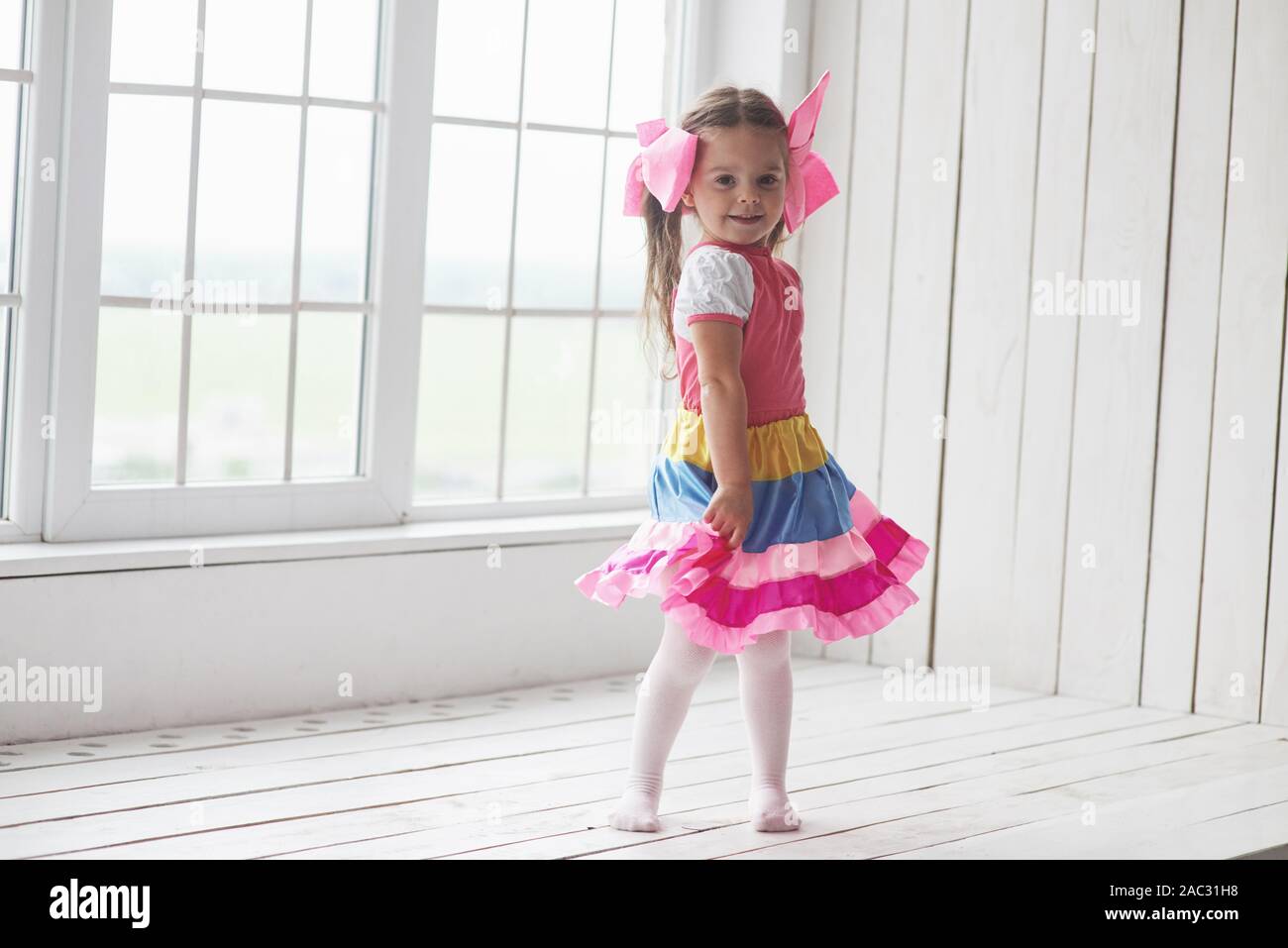 Child standing beside the windows in white room and posing for the ...