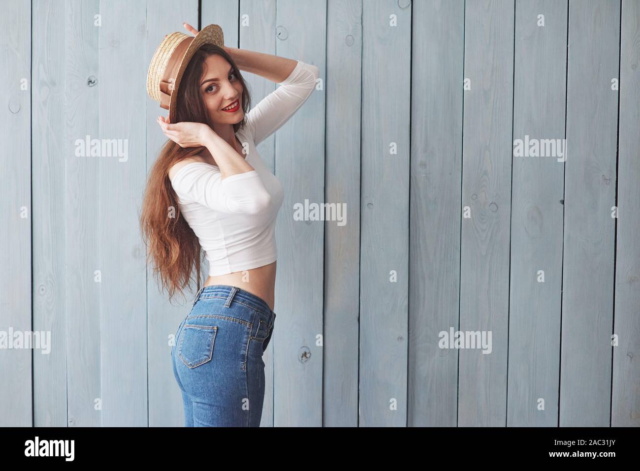 Girl in the hat turned sideways to the camera. Standing at the wooden ...