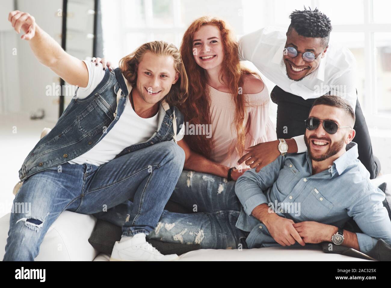 Office friends have cheerful time sitting and laying on the white sofa ...