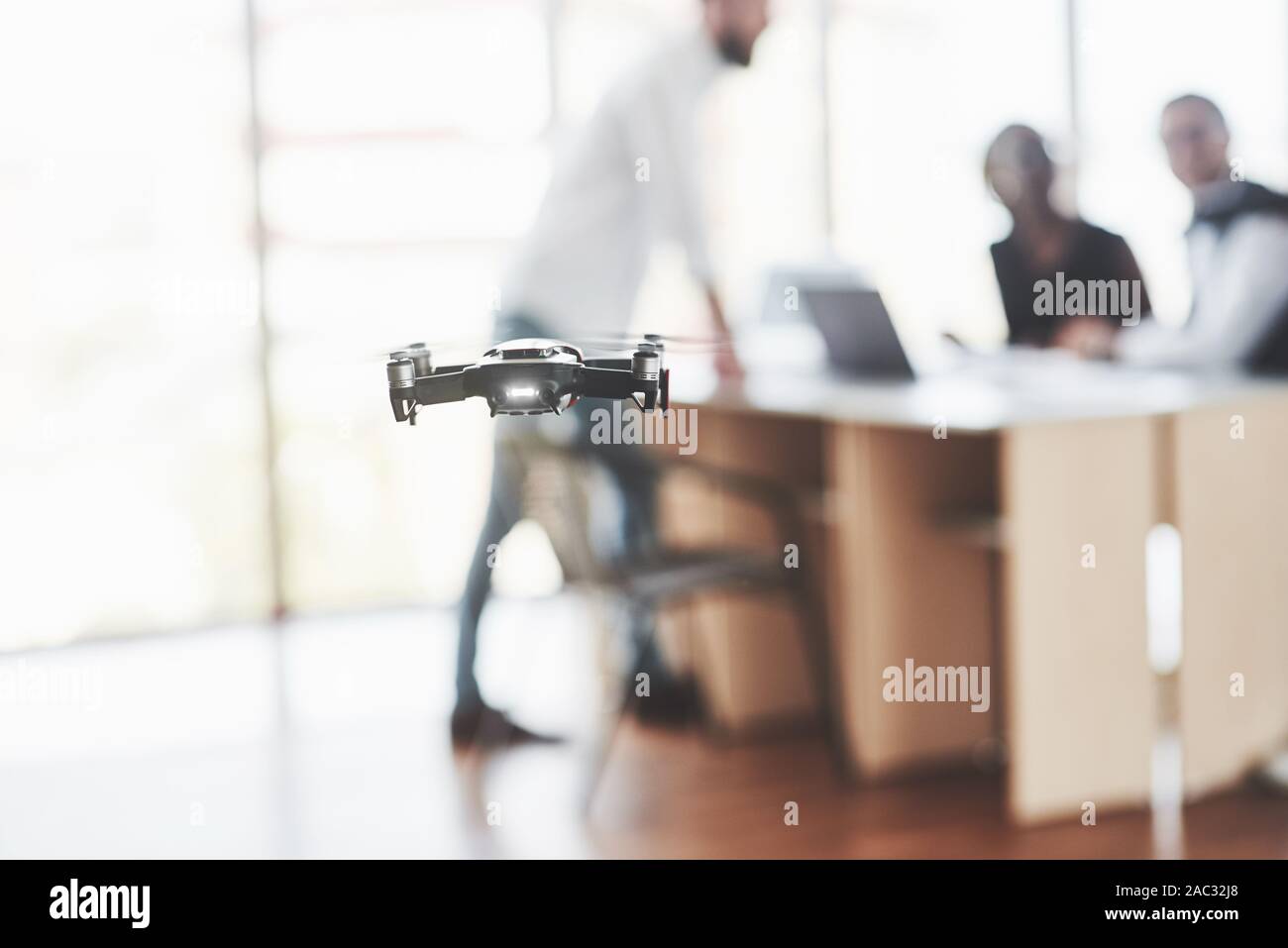 Flying drone is in the office room. Employees sitting and watching for ...