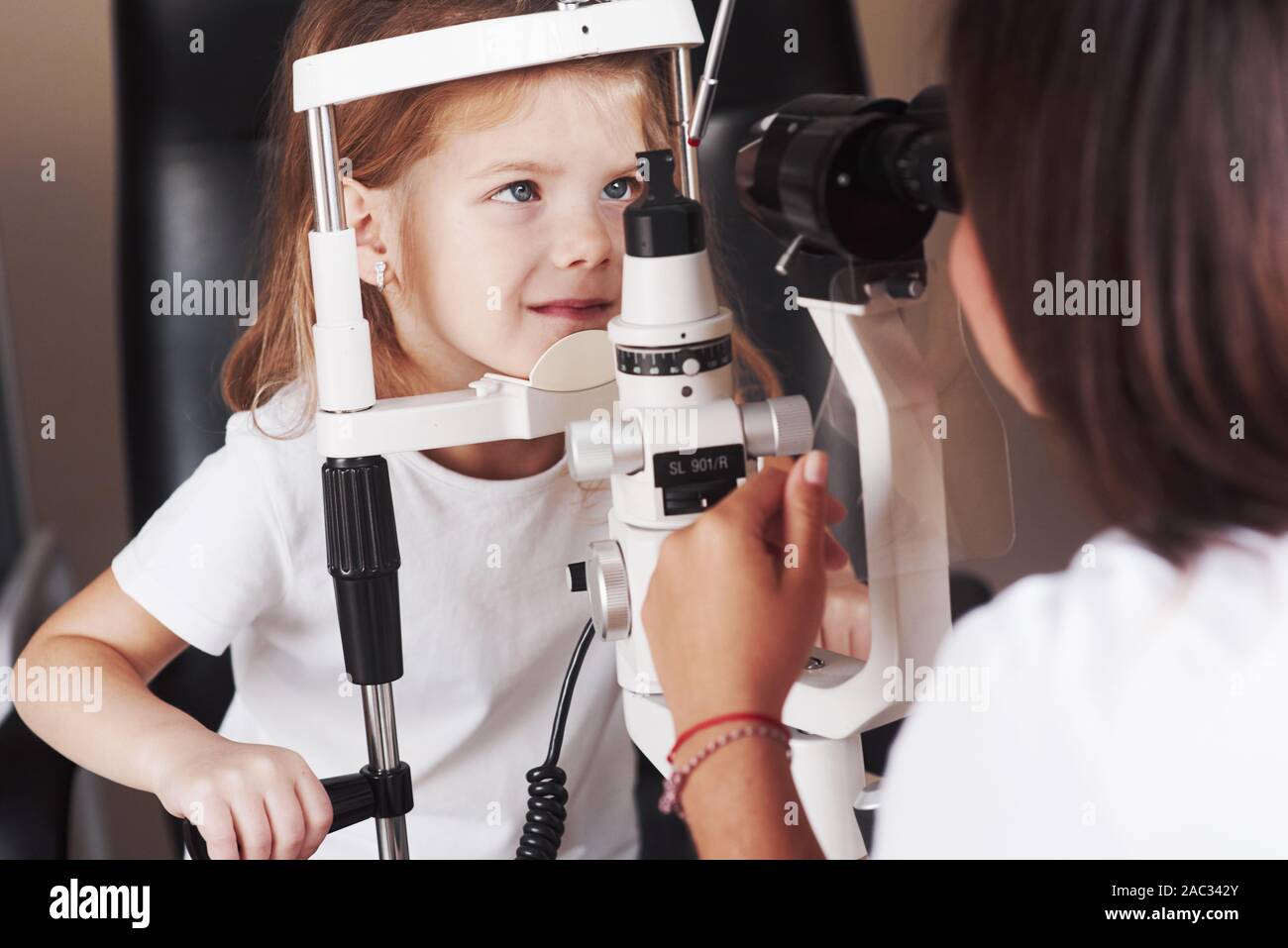 Look straight. Little girl have test for his eyes with special optical ...