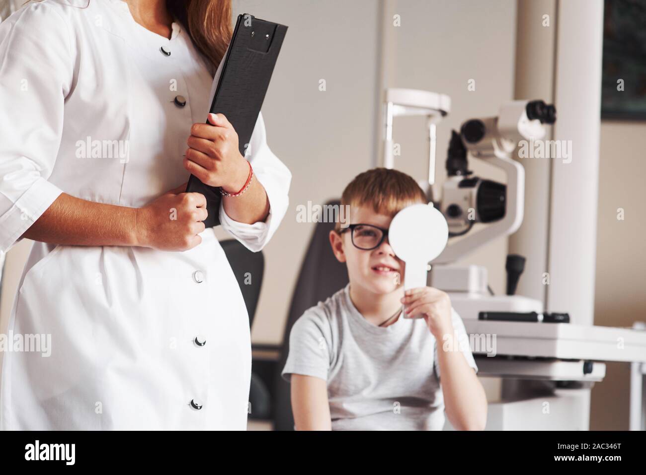 Devices at background. Woman with documents tests the visual acuity of ...