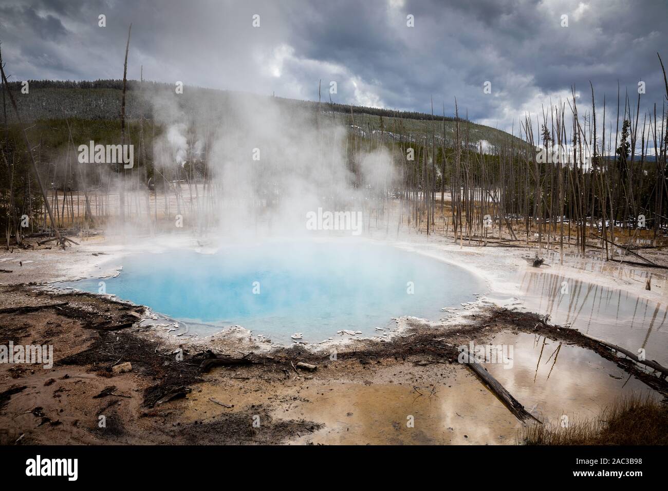 Blue boiling geyser basin with smoke in dry environment of Yellowstone ...