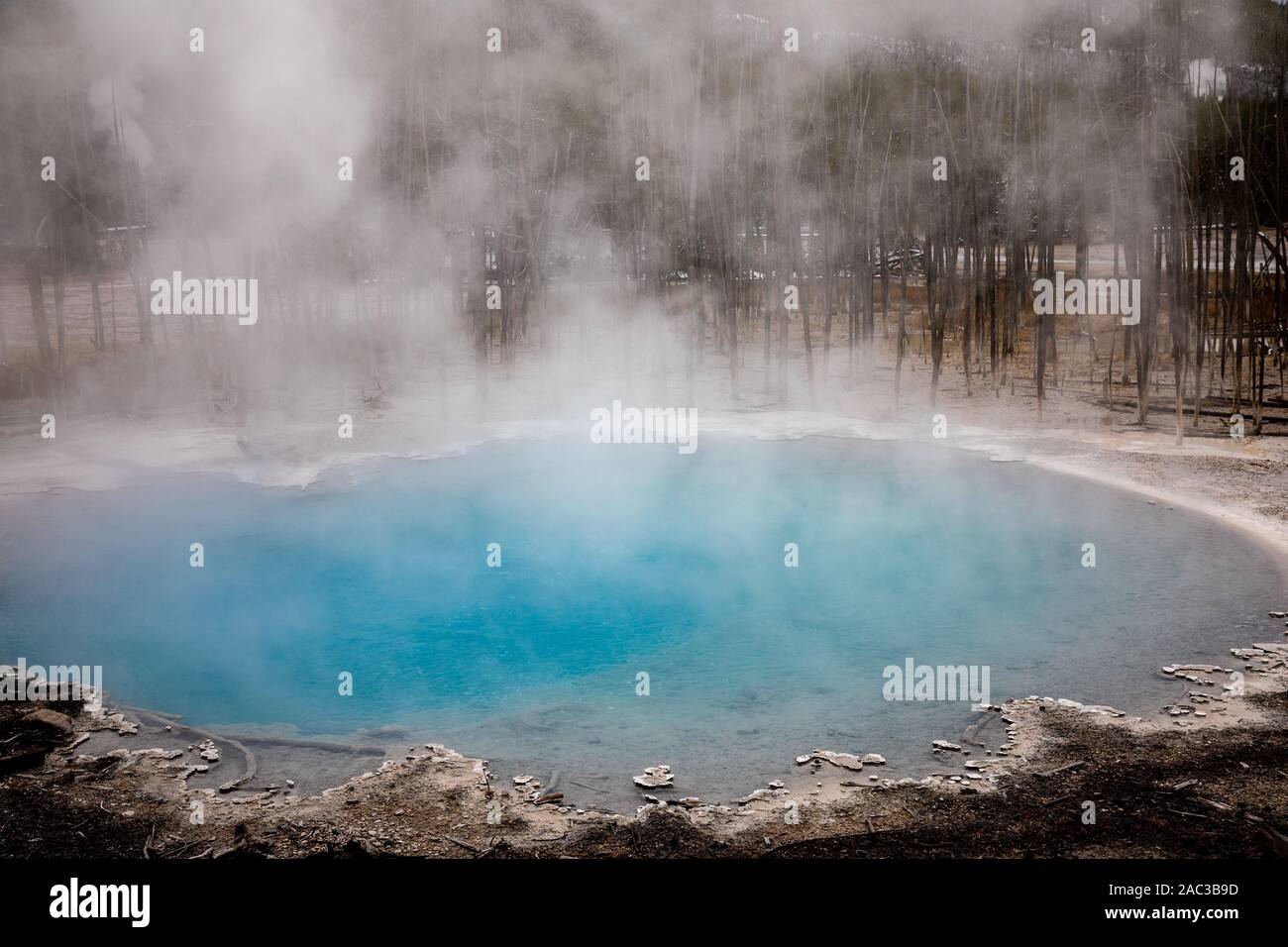 Blue boiling geyser basin with smoke in dry environment of Yellowstone ...