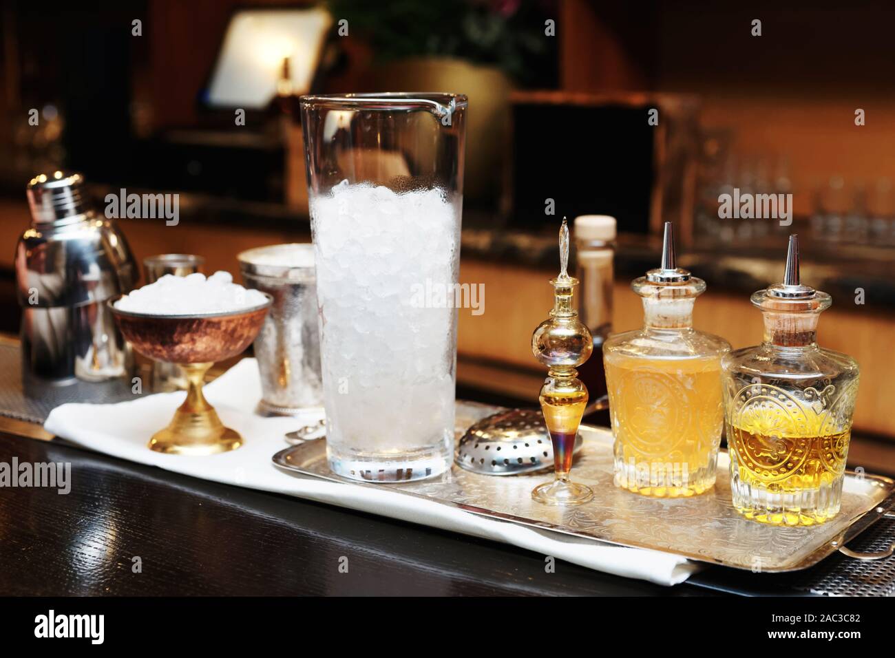 Bitters, infusions and mixing glass with ice on bar counter, toned ...