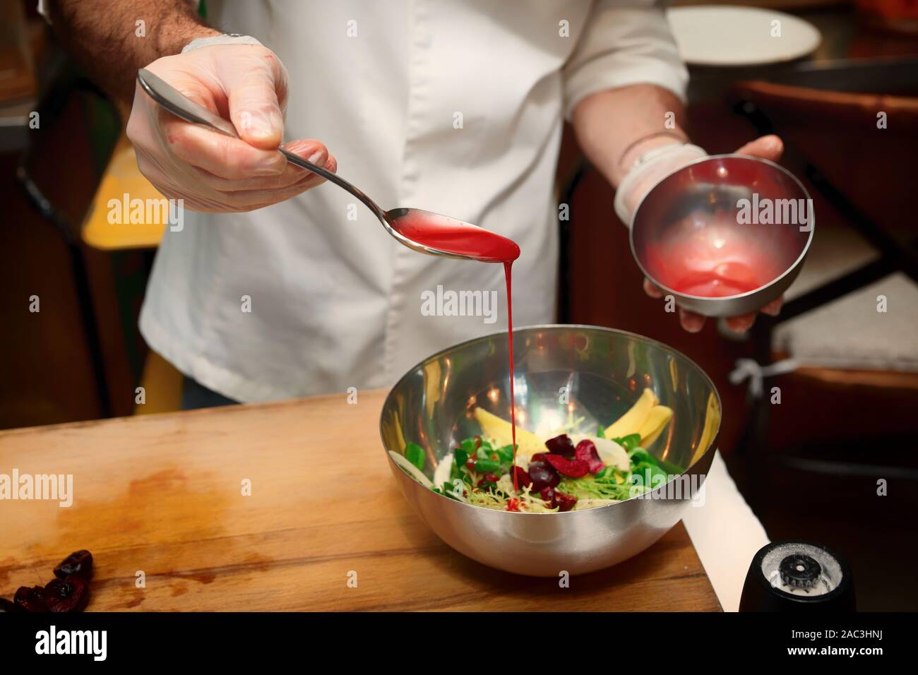 Chef is adding sauce to bowl with vegetable appetizer, professional ...