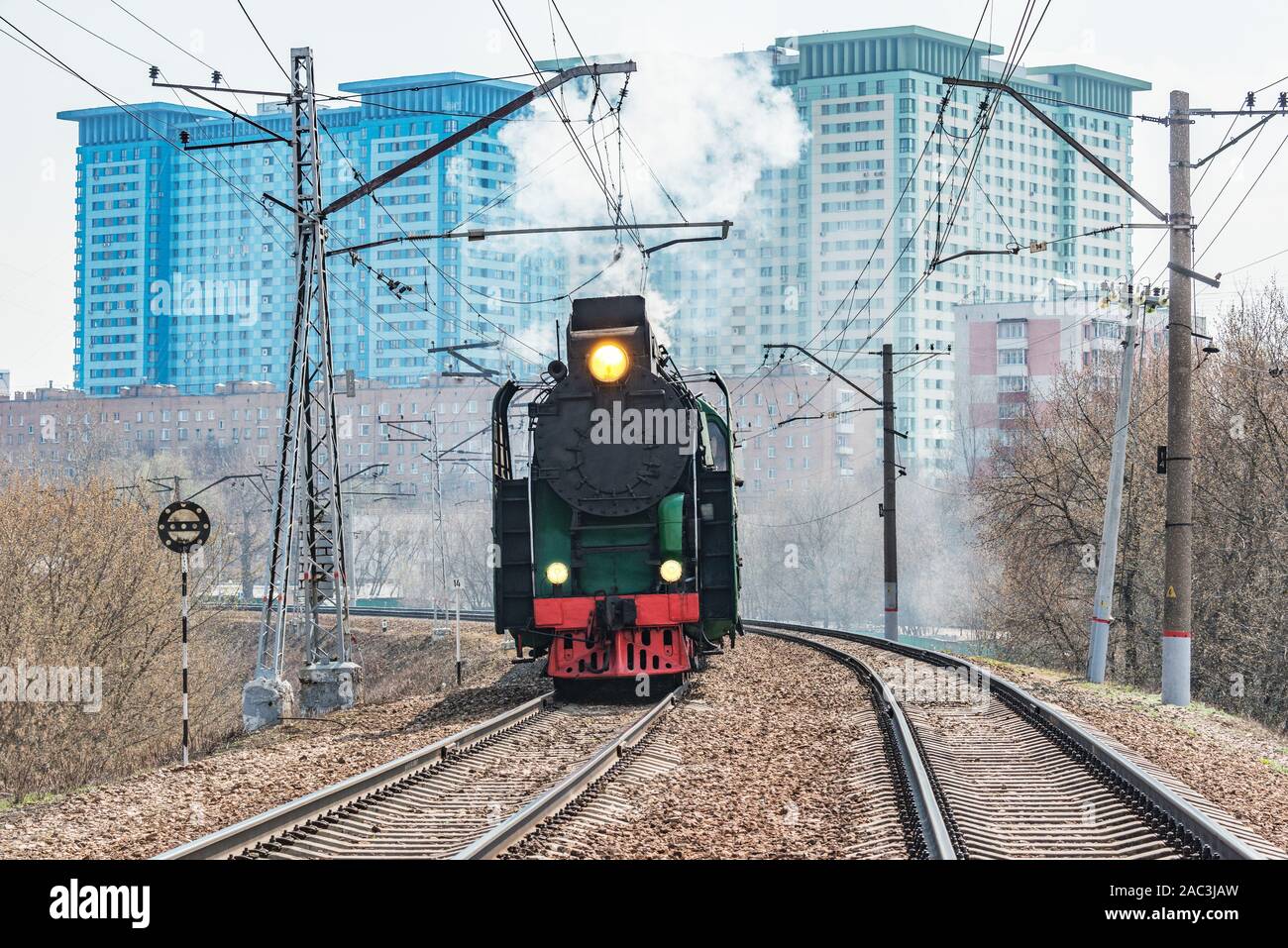 Steam train moves on the city background Stock Photo - Alamy