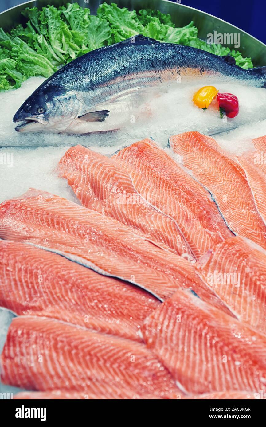 Fresh salmon, fillet and whole, on ice display in supermarket, toned ...