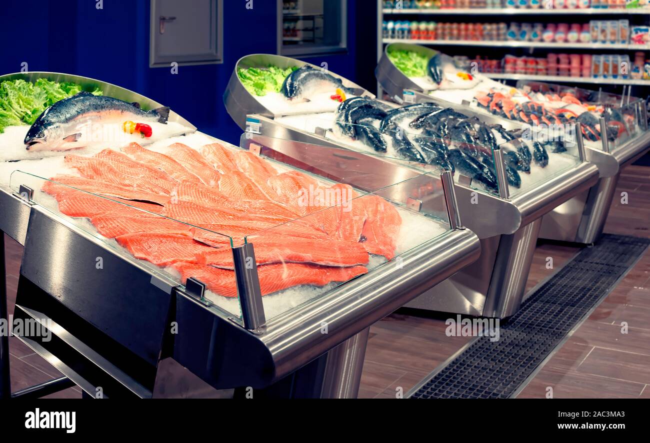 Fresh salmon, fillet and whole, on ice in a food store, toned image ...