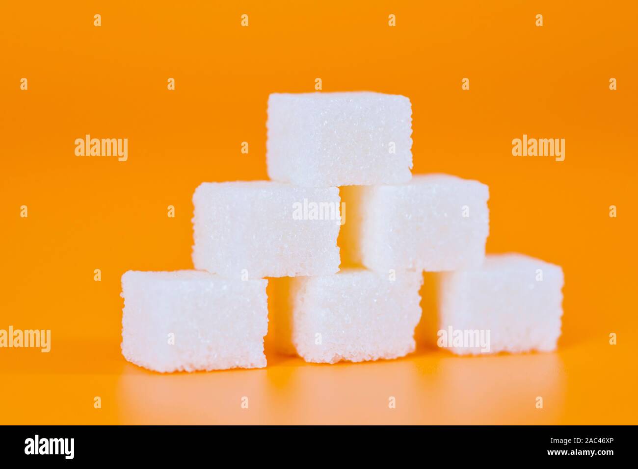 Pyramid from sugar cubes on a orange background. The pyramid is made up ...
