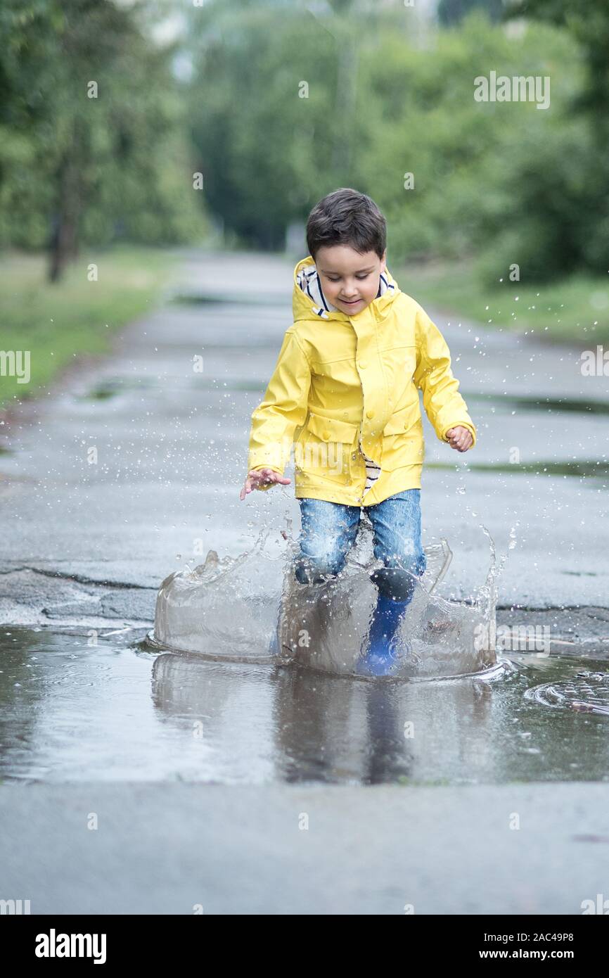 A wet child is jumping in a puddle. Fun on the street. Tempering in ...