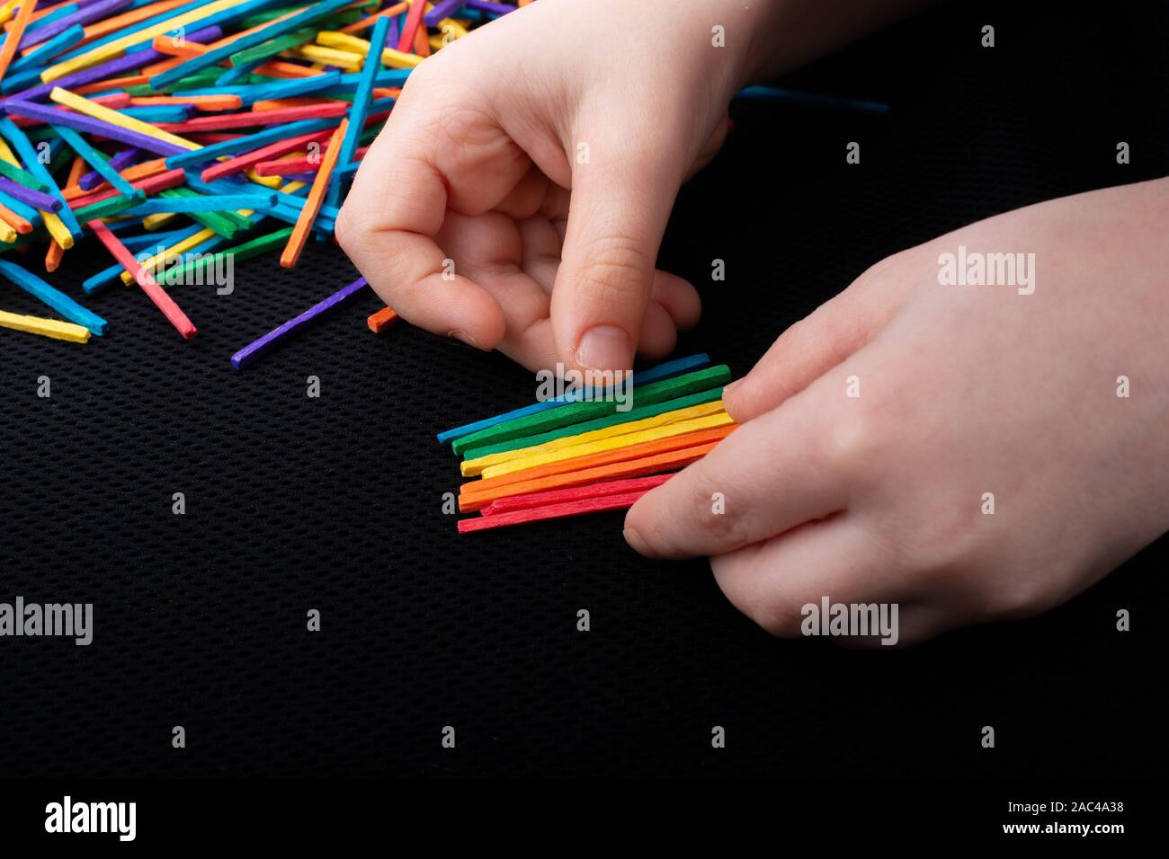 Kid playing with coloured wooden sticks for creativity on white ...