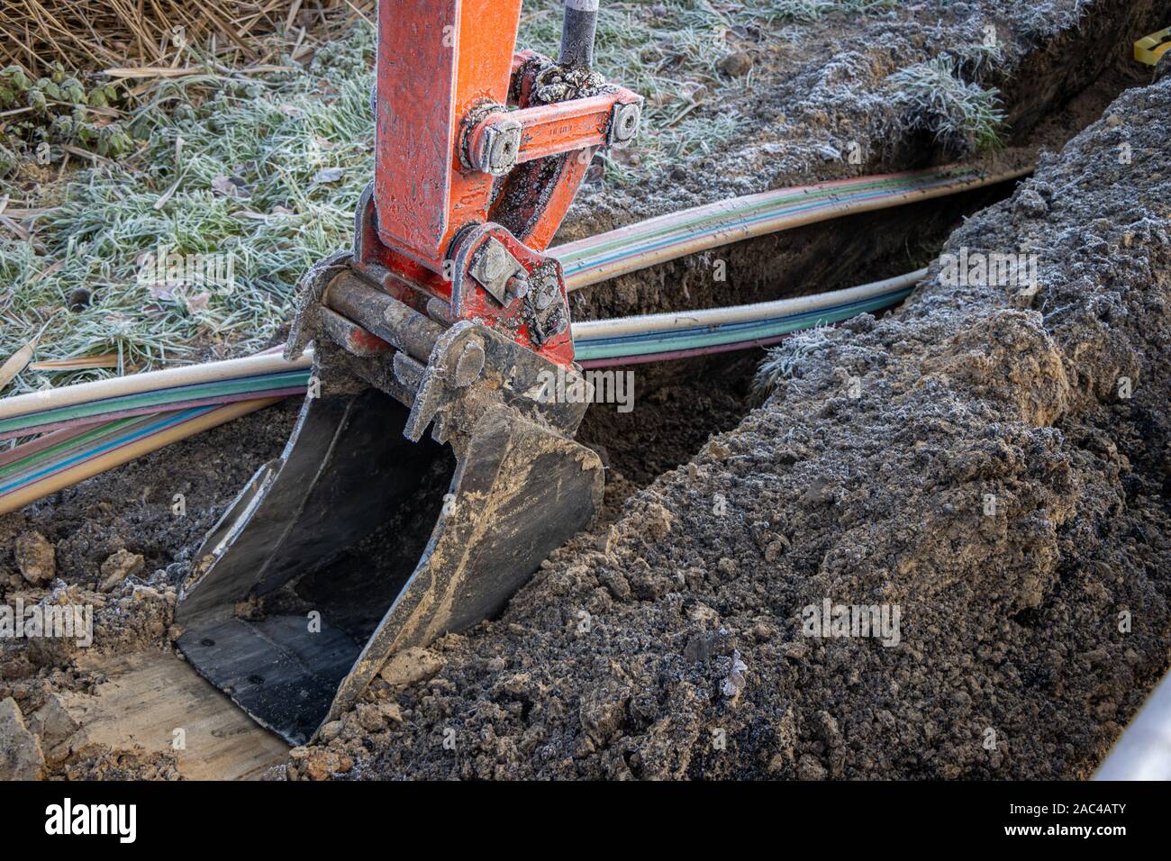 an excavator digging a trench to lay a high-speed Internet DSL cable ...