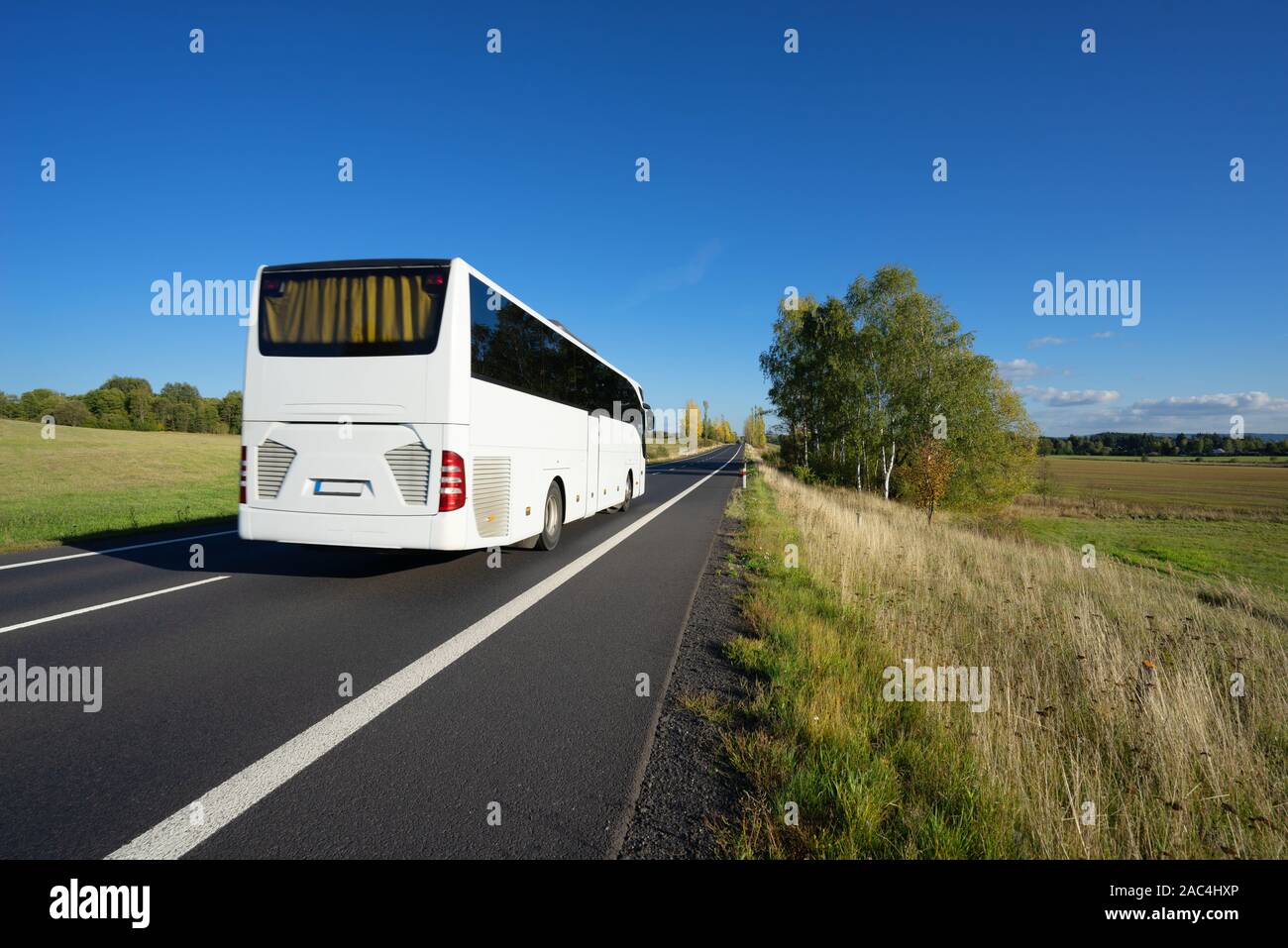 White bus driving on asphalt road in autumn rural landscape Stock Photo ...