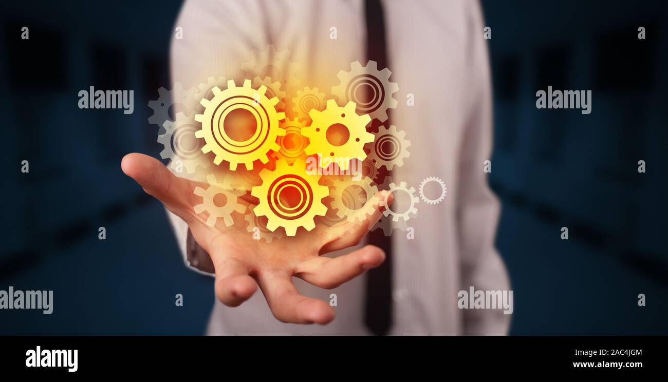 Hand holding gears in his hand Stock Photo - Alamy