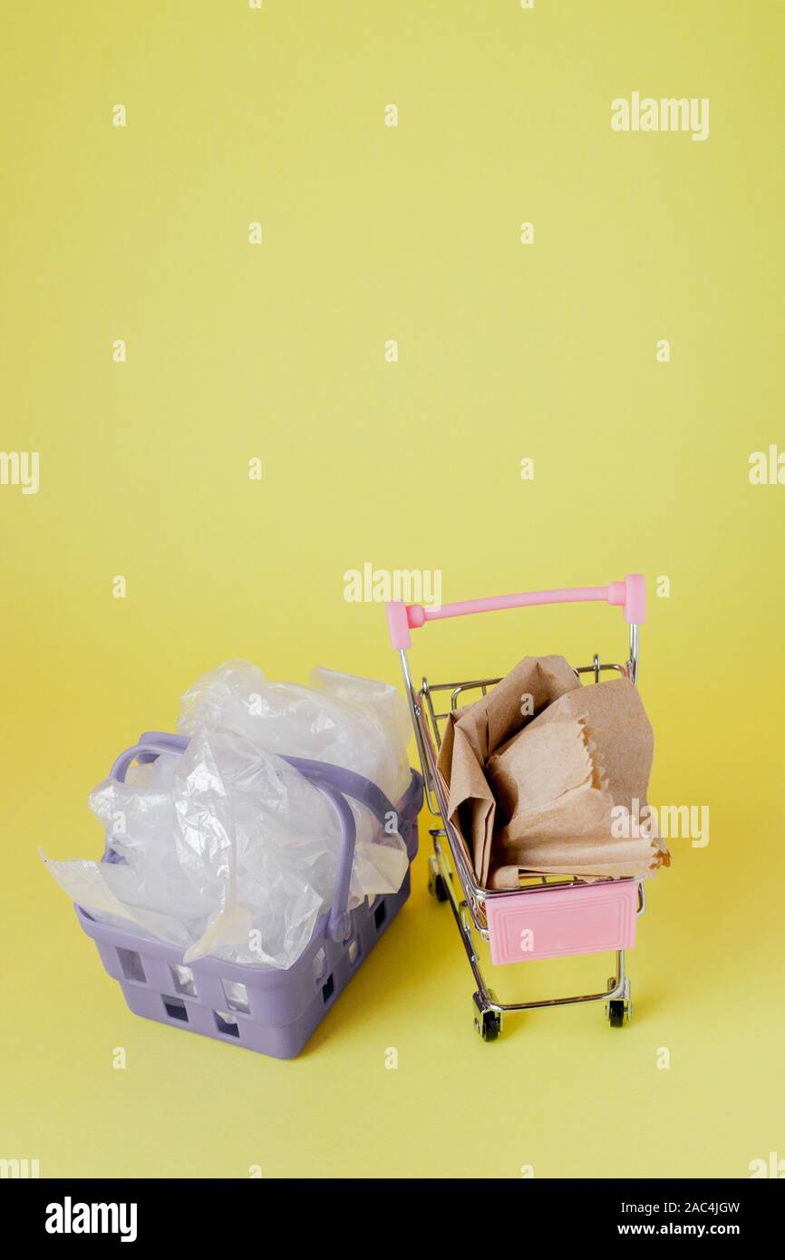 polythene and paper bags in a shopping basket on a yellow background ...