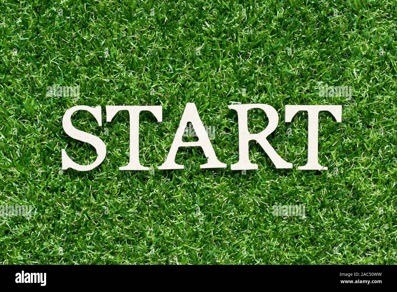 Wood alphabet letter in word start on artificial green grass background ...