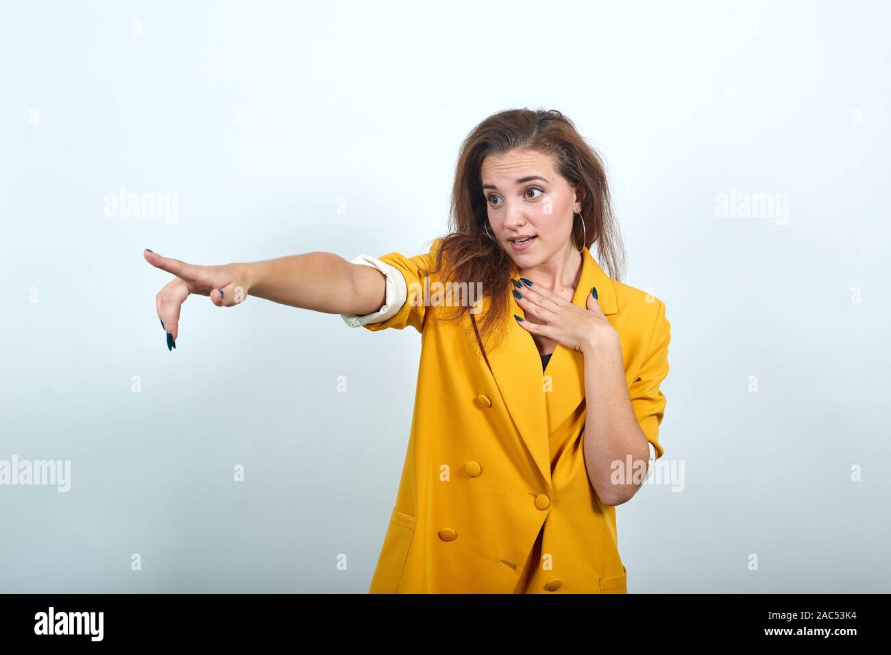 Pleasant woman in yellow jacket keeping hand on chest, pointing into ...