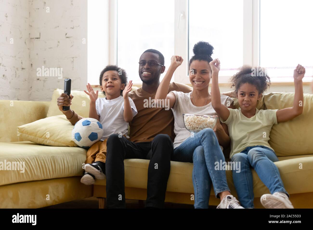 Happy biracial family with kids watch football at home together Stock ...