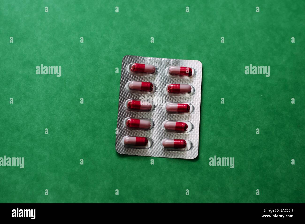 Pack of red and white medicine capsules on a green background Stock ...