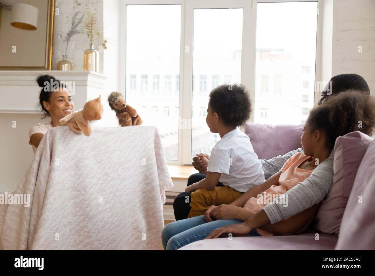 Smiling biracial mum show puppet play to little kids Stock Photo - Alamy