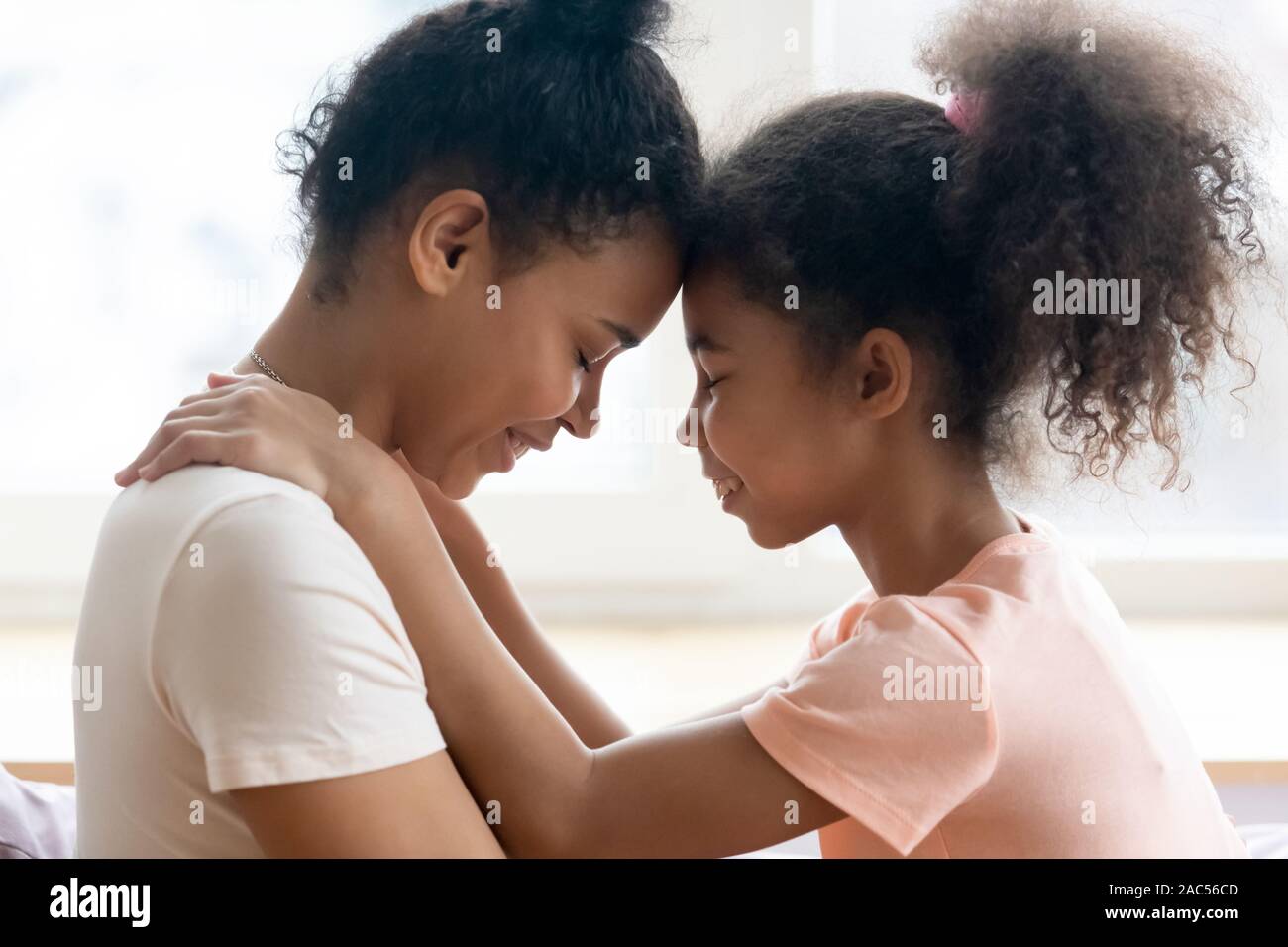 African American mom and daughter touch forehead enjoying tender moment ...