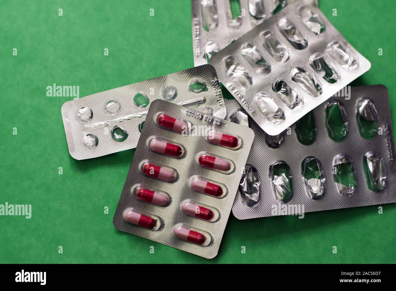 Pack of red and white medicine capsules on a green background Stock ...