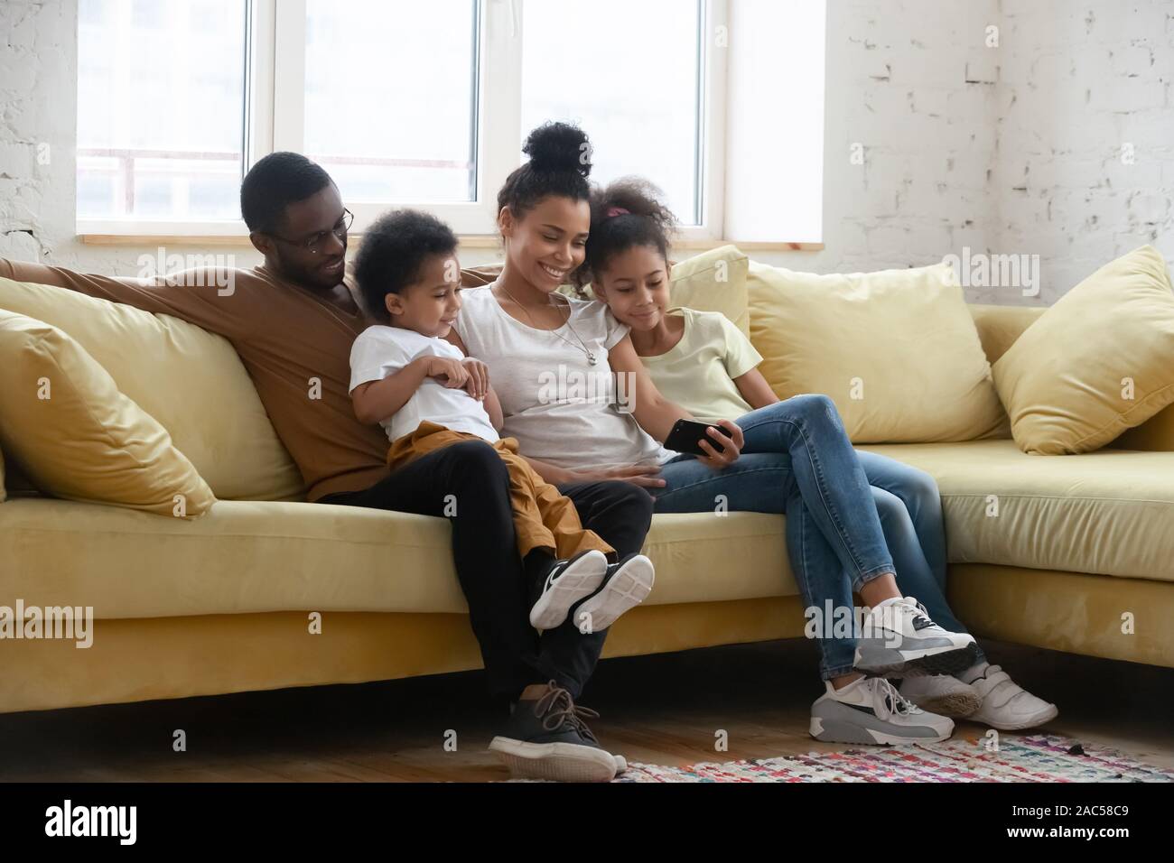 Happy biracial family with kids using cellphone together Stock Photo ...