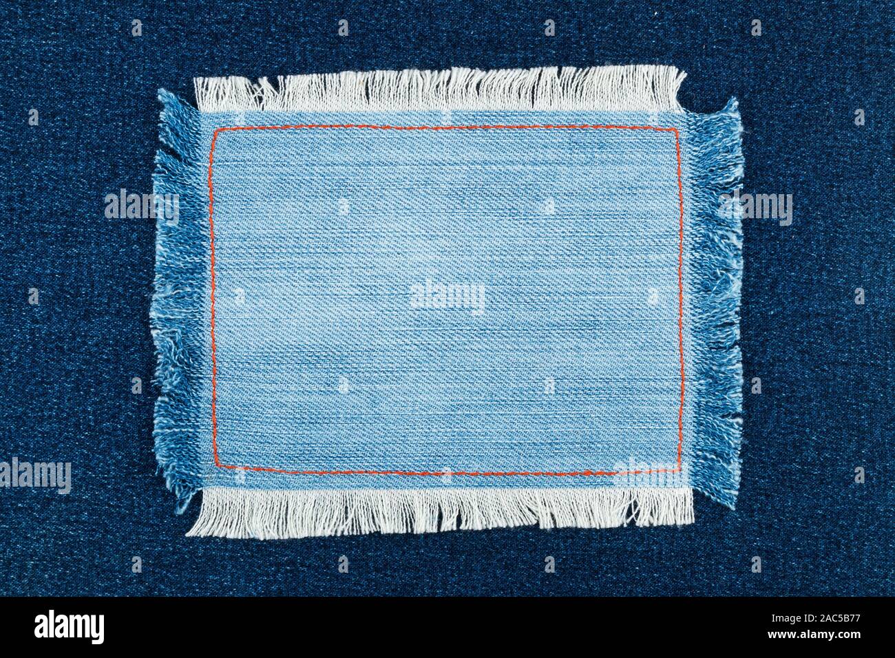Torn denim frame with fringe on the edges lying on denim, text place ...