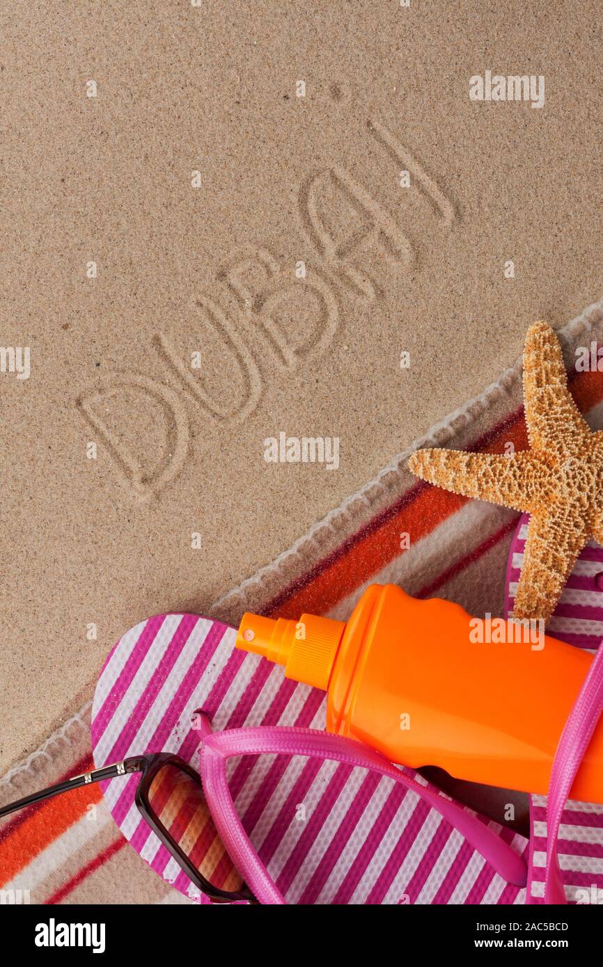 Word DUBAI written in sand with beach accessories. Travel background ...