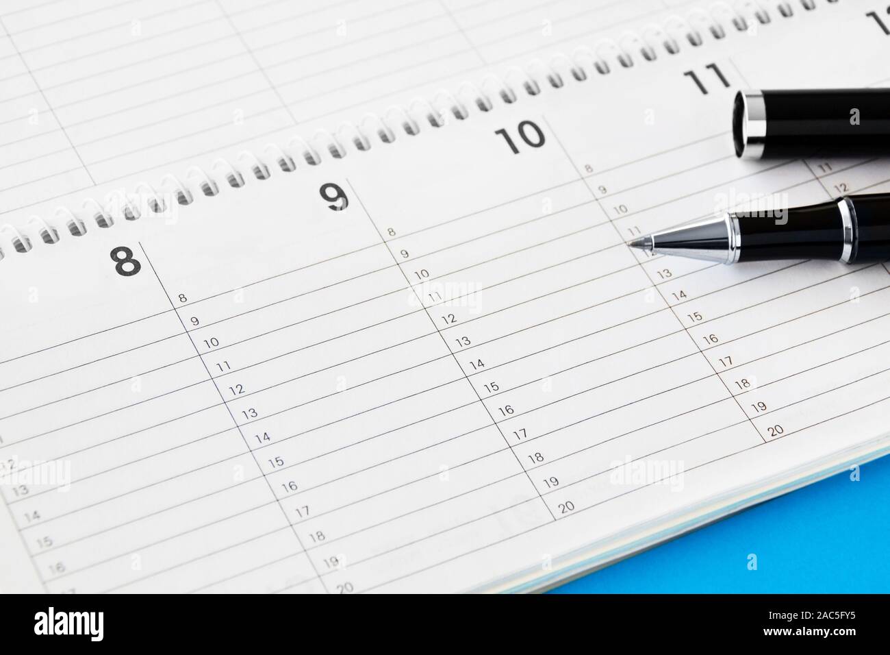 Calendar with pen and blue background Stock Photo - Alamy