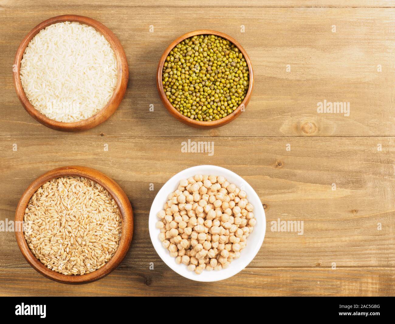 Rice, oat, chick pea, green gram in cups on brown wooden background ...