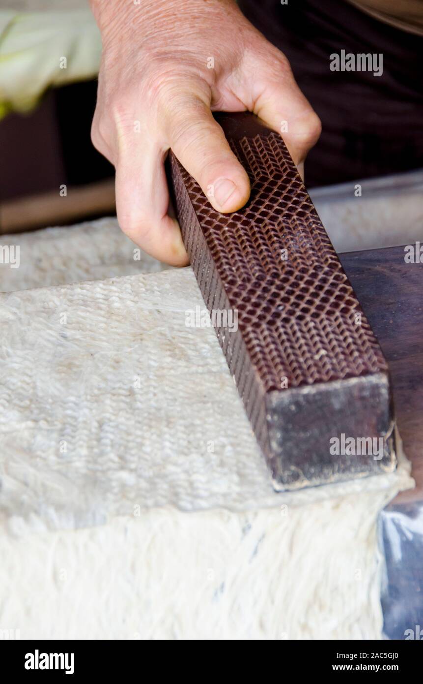 Roen Hufford beats paper mulberry bark with a carved wooden beater as ...