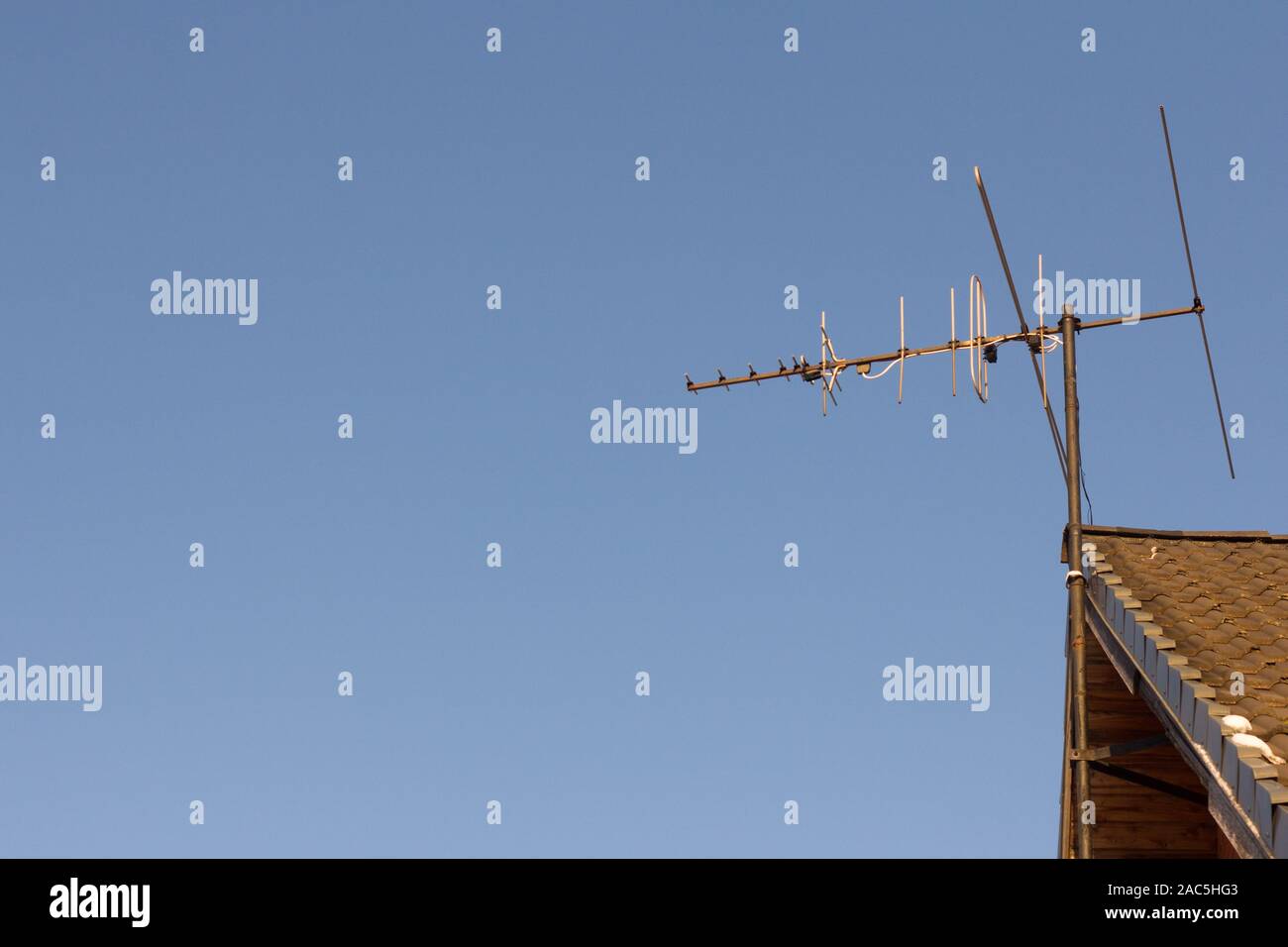 TV analog antenna on the roof of the house, against the blue sky Stock ...