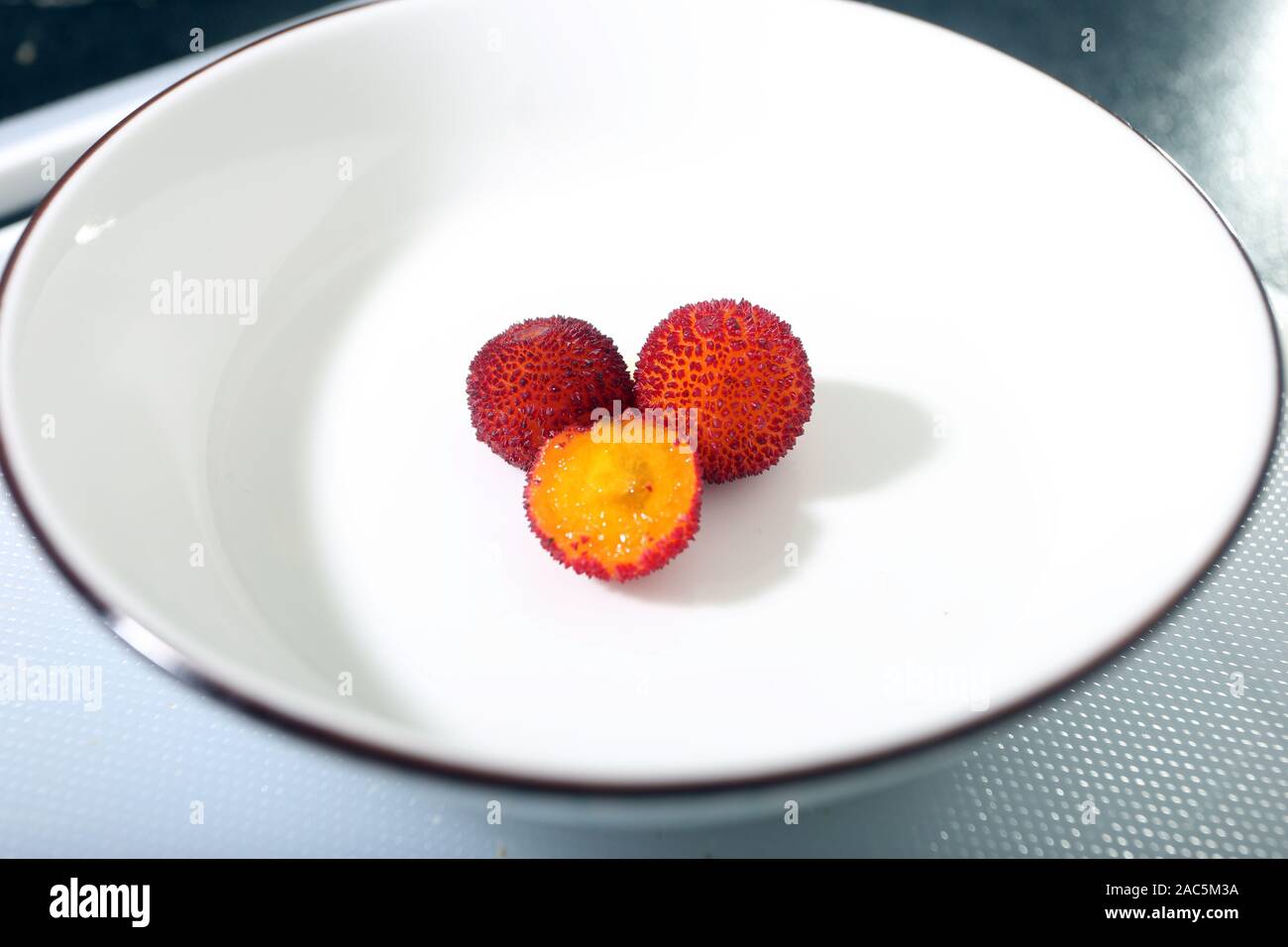 the arbutus tree: two ripe fruits in the saucer and one cut into slices ...