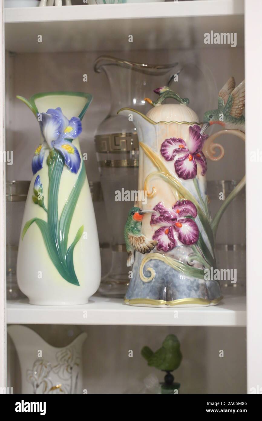 Beautiful white jugs with floral patterns on a shelf in a cabinet in ...