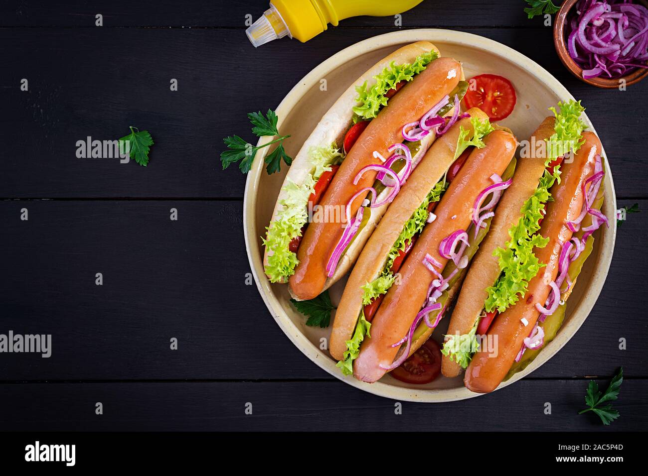Hot dog with sausage, pickled cucumber, tomatoes, red onions and ...