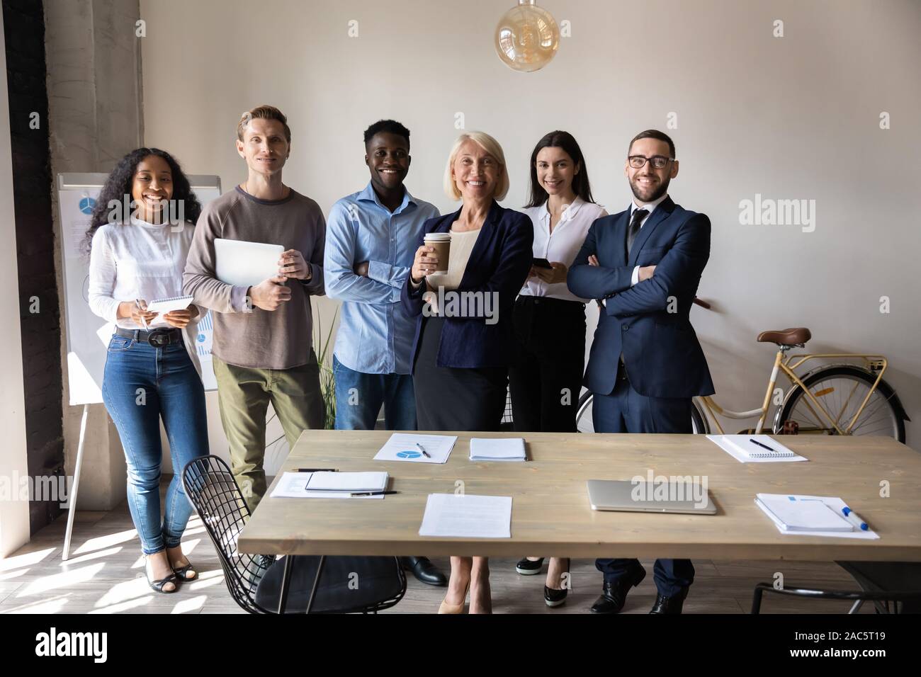 Positive middle aged female leader posing with team Stock Photo - Alamy